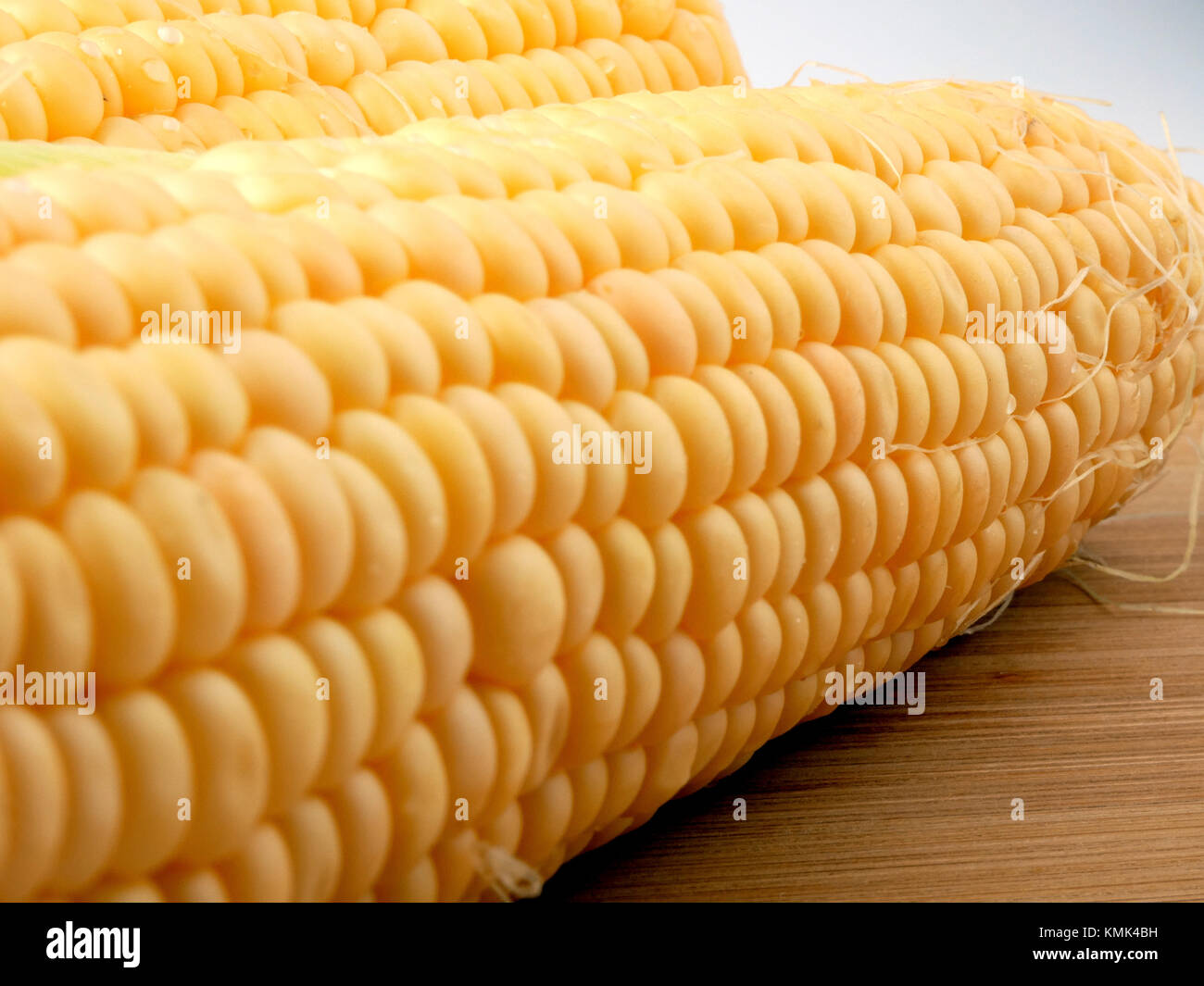 Corn cob on wooden plank isolated on white Stock Photo - Alamy