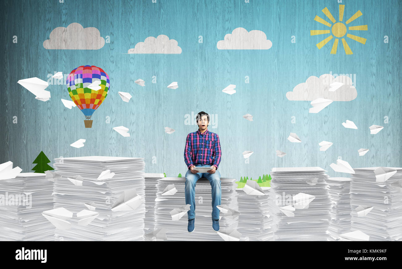 Young man sitting on pile of paper documents Stock Photo - Alamy
