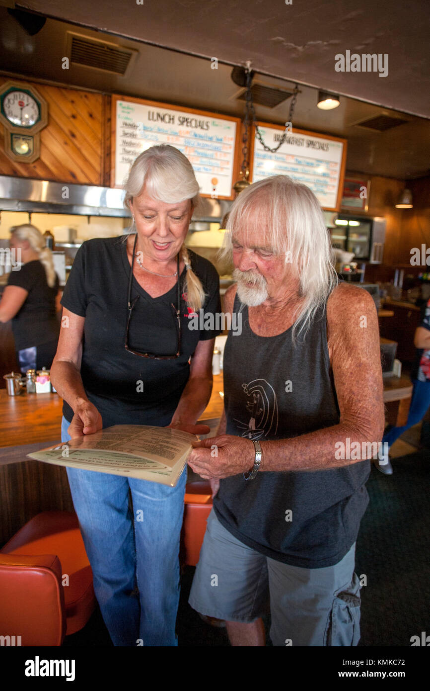 The friendly hostess of a Costa Mesa, CA, restaurant shows the menu to ...