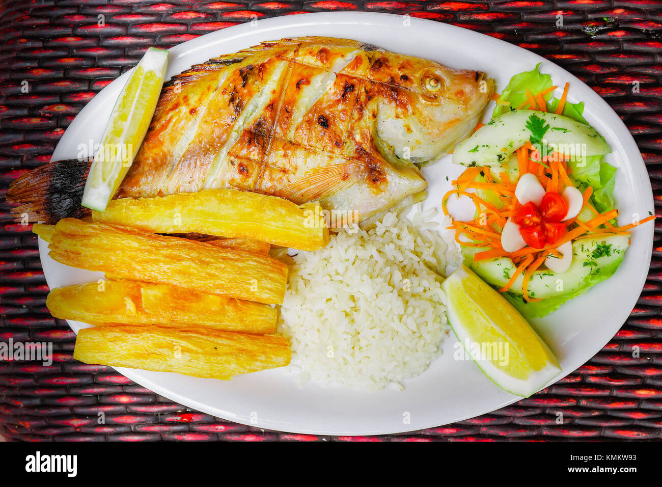 Above view of fried fish served with side salad, rice, and yucca served ...