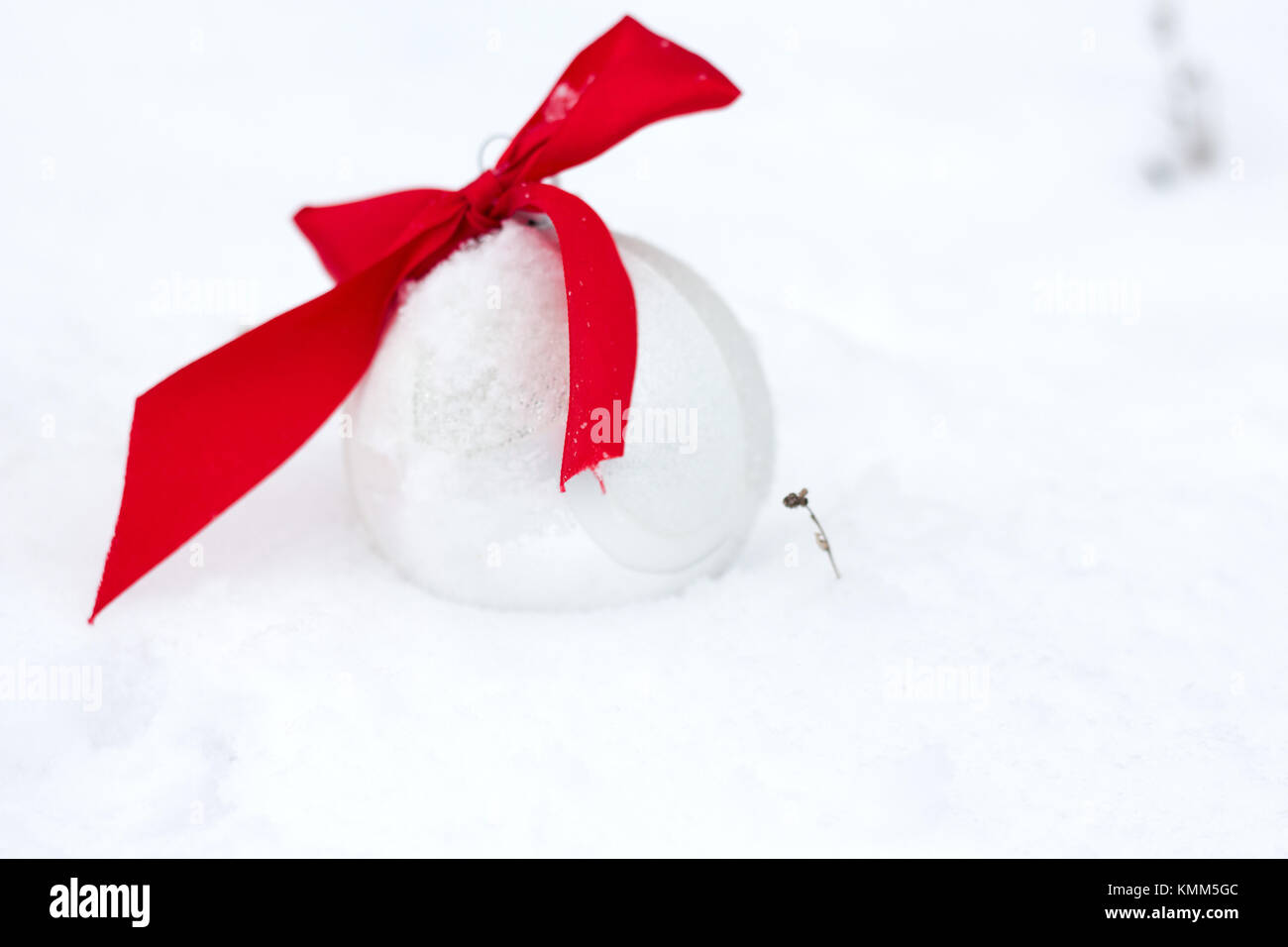 Christmas ball with red ribbon in a snow setting with white background ...
