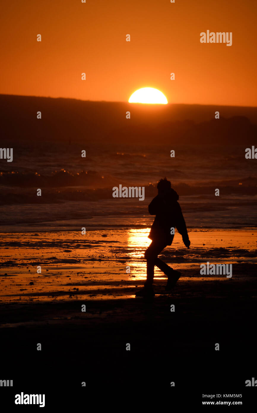 Person walking through a sunset at the beach Stock Photo - Alamy