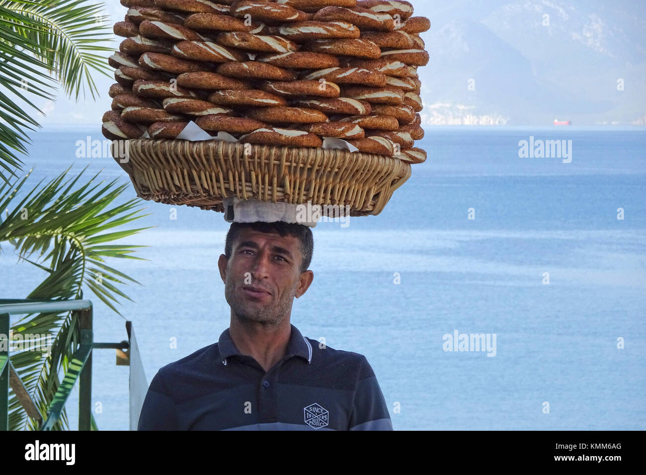 Turkish man poises simits on head, simit is similar to a bagel, covered ...