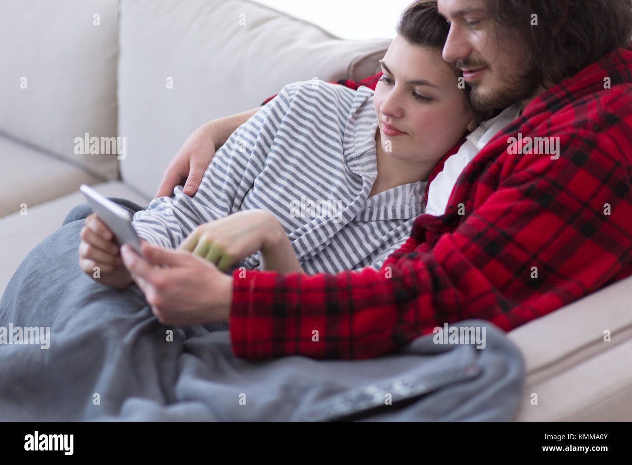 Young couple relaxing at home using tablet computers reading in the ...