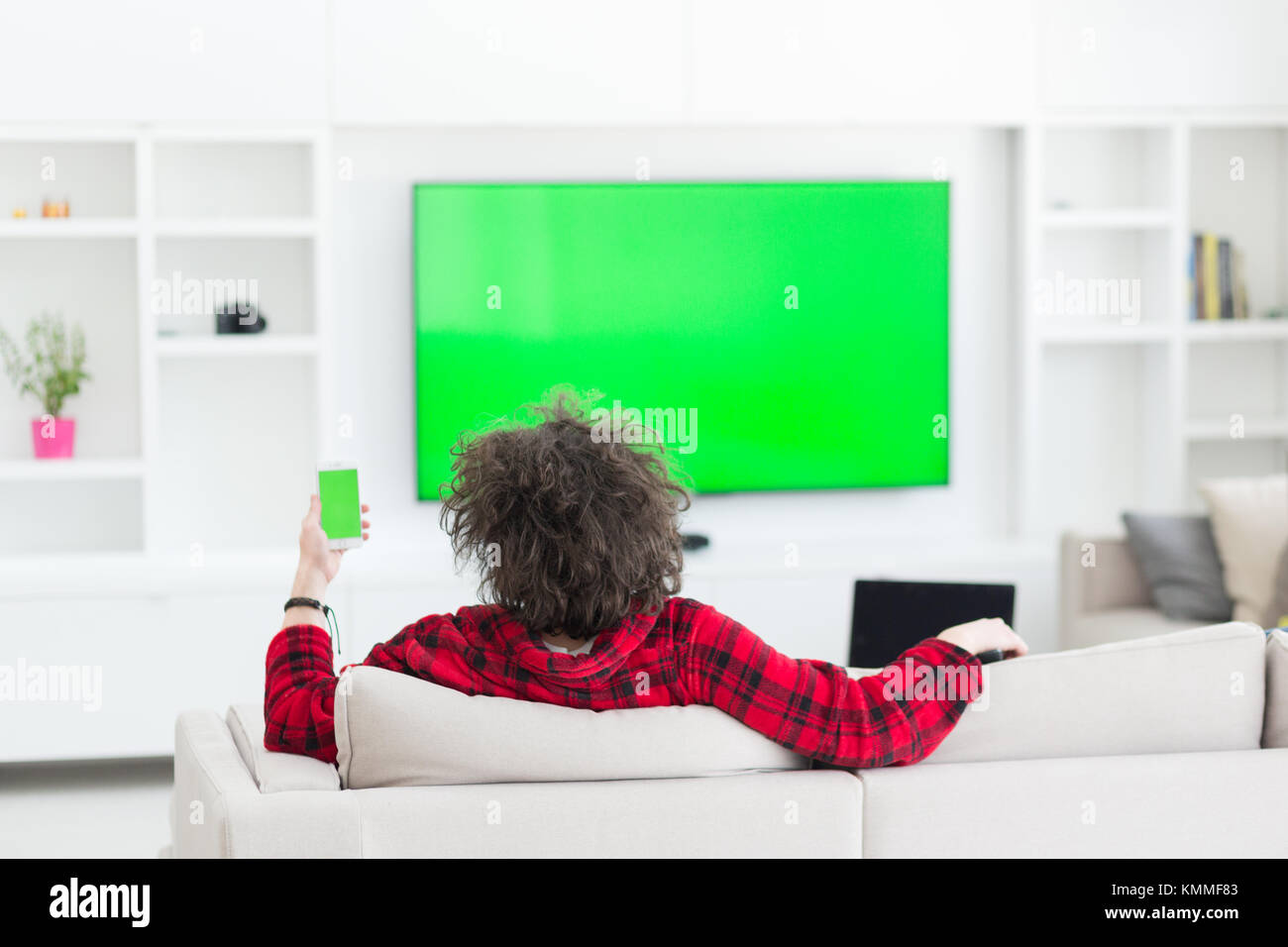 young handsome man in bathrobe enjoying free time watching television ...
