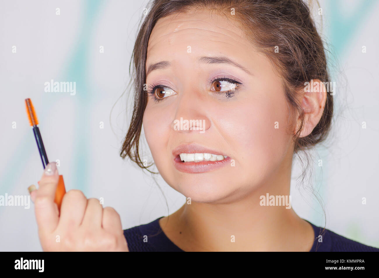 Close up of worried young woman doing a mess using a eye mascara in her ...