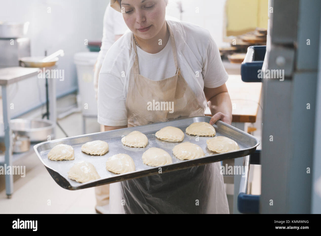 Cook puts pies into stove for baking Stock Photo - Alamy