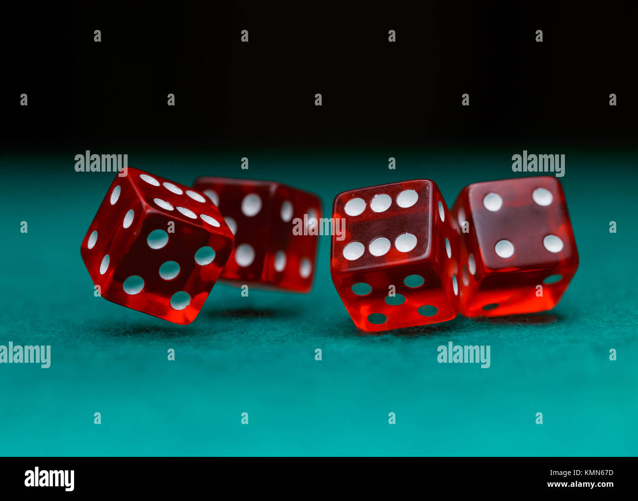 Picture of several red dice falling on green table on black background ...
