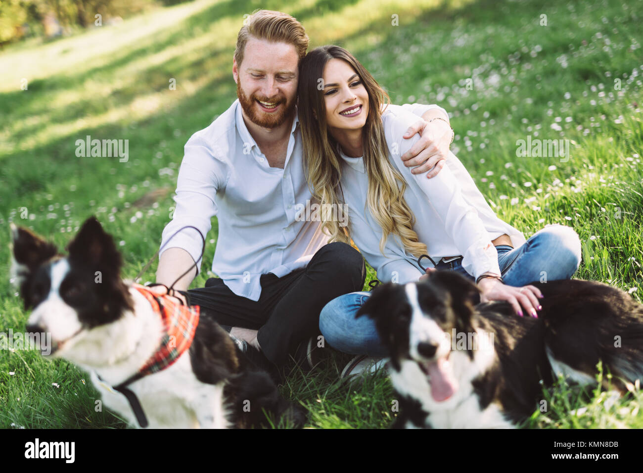 Beautiful couple cuddling and walking dogs outdoors Stock Photo - Alamy