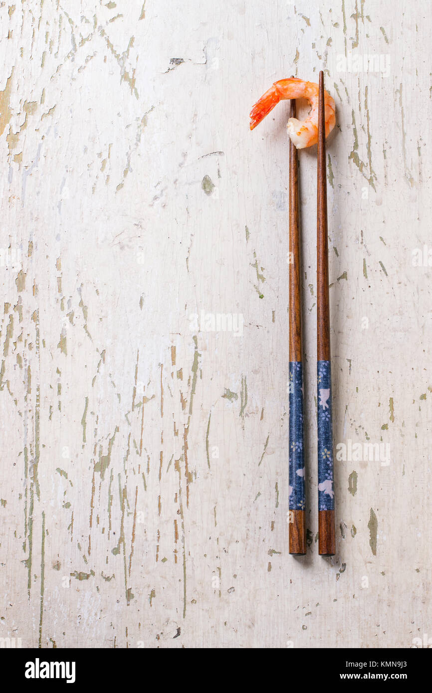 Fried shrimp in dark chopsticks over white wooden background Stock ...