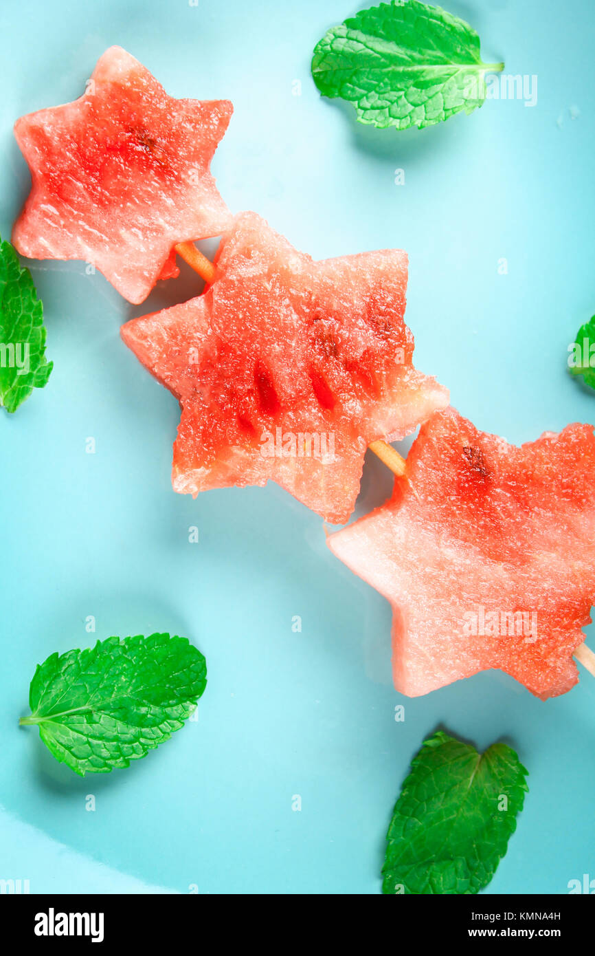 Watermelon in the form of stars on skewers with leaves of mint lies on ...