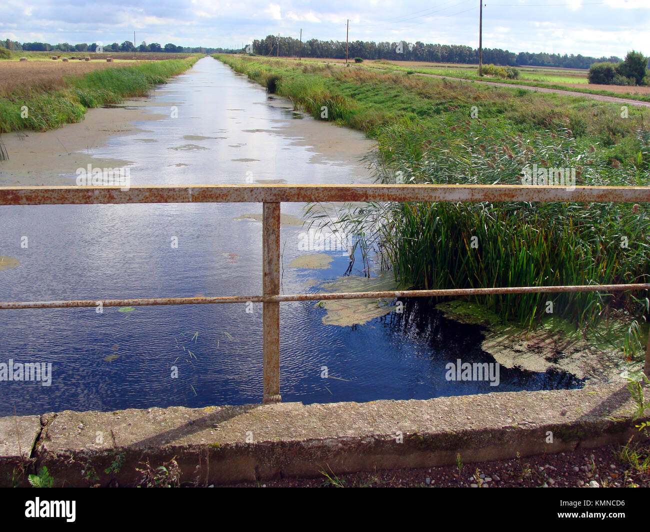 Field drainage and irrigation system channel with old concrete bridge ...