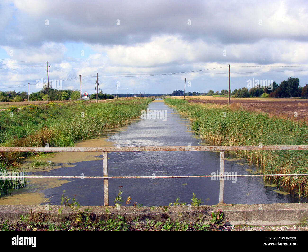 Field drainage and irrigation system channel with old concrete bridge ...