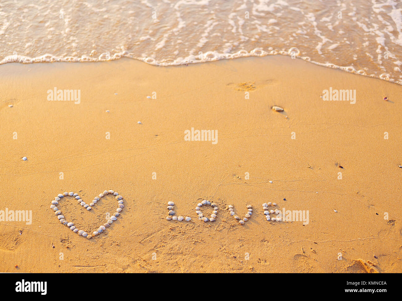 On the sand shells lined with heart and the word love Stock Photo - Alamy
