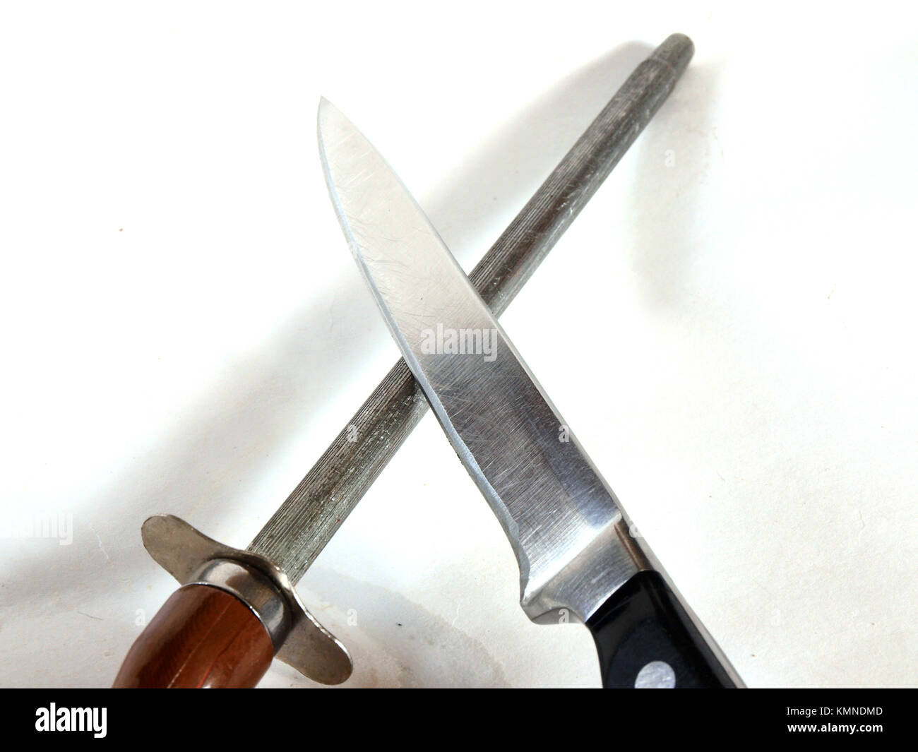 Knife sharpening on special steel stick close up on white background ...