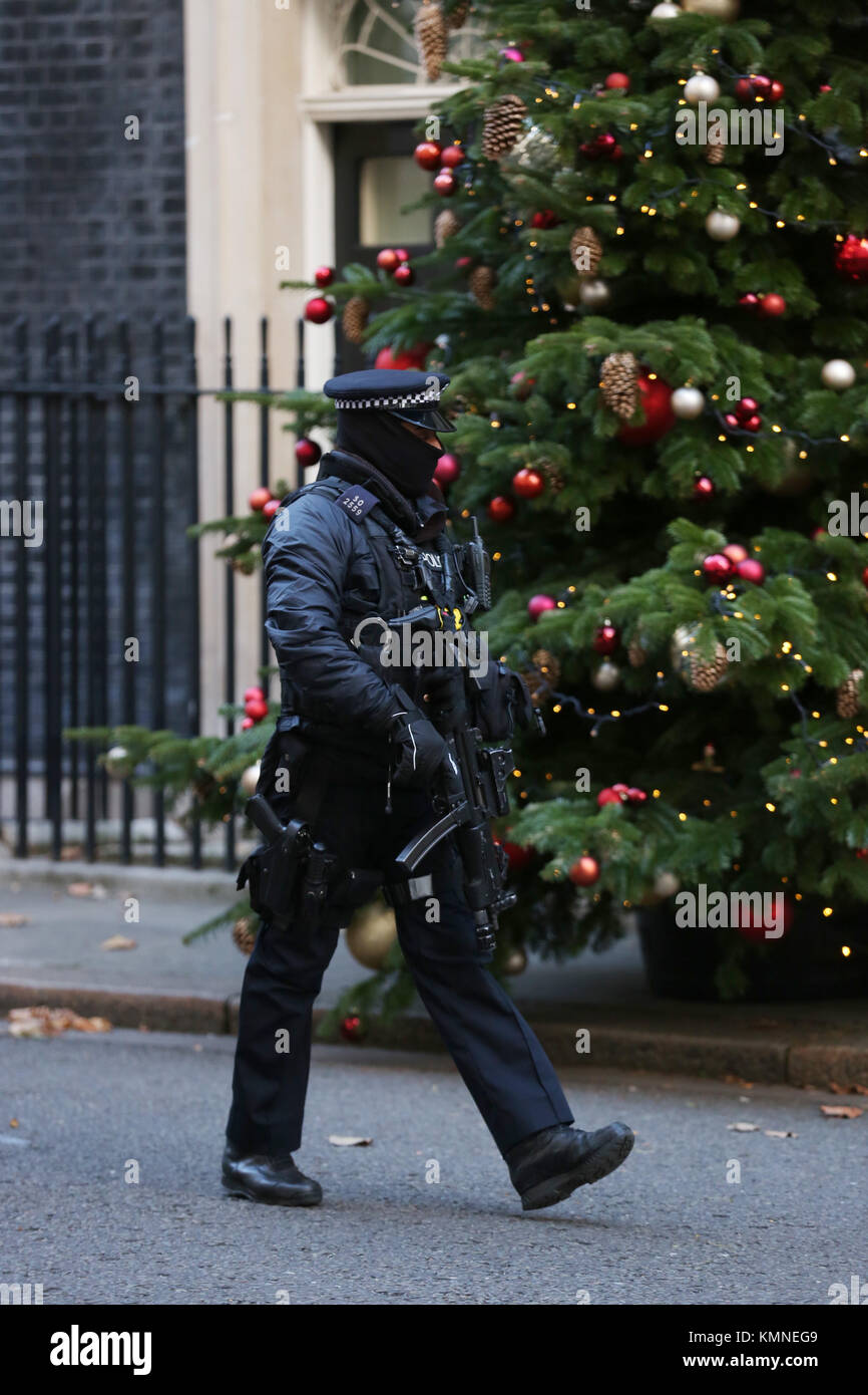 An armed police officer walks past a Christmas tree outside the door of ...
