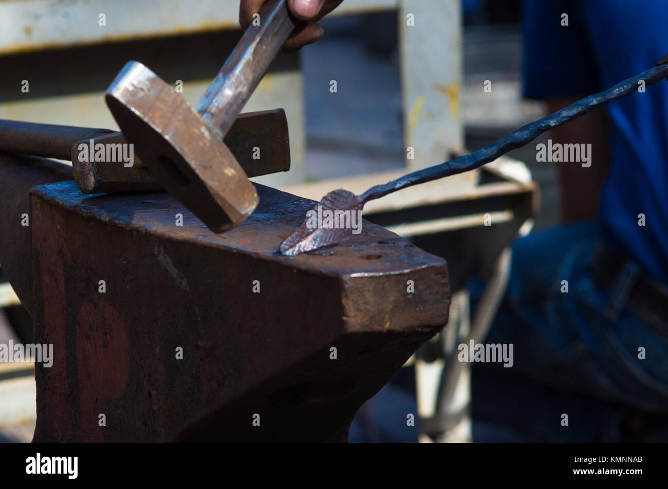 blacksmith performs the forging of hot glowing metal on the anvil ...