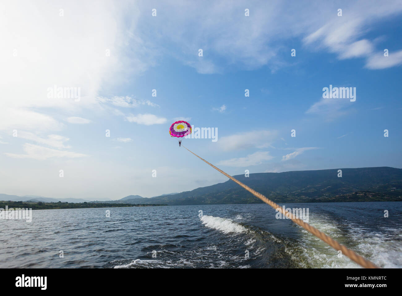 Parachute Gliding sailing woman pulled by rope attached to boat over ...