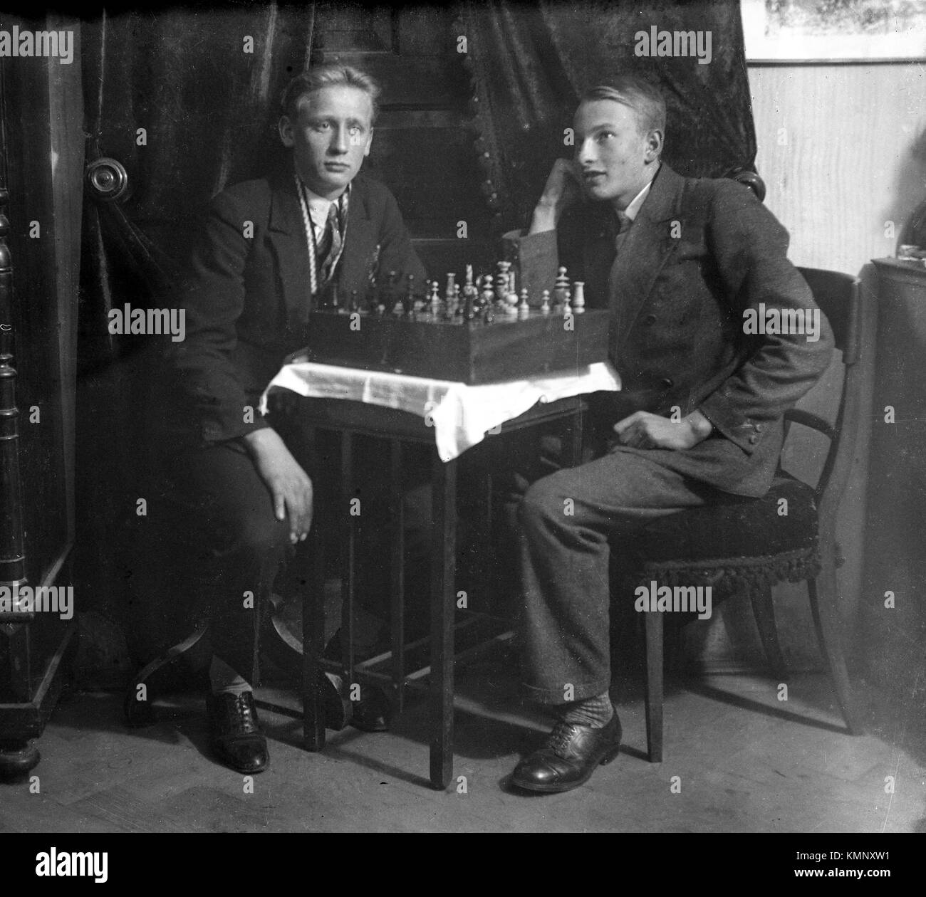 C1930 Two young men pose while playing a game of Chess. Photograph by ...