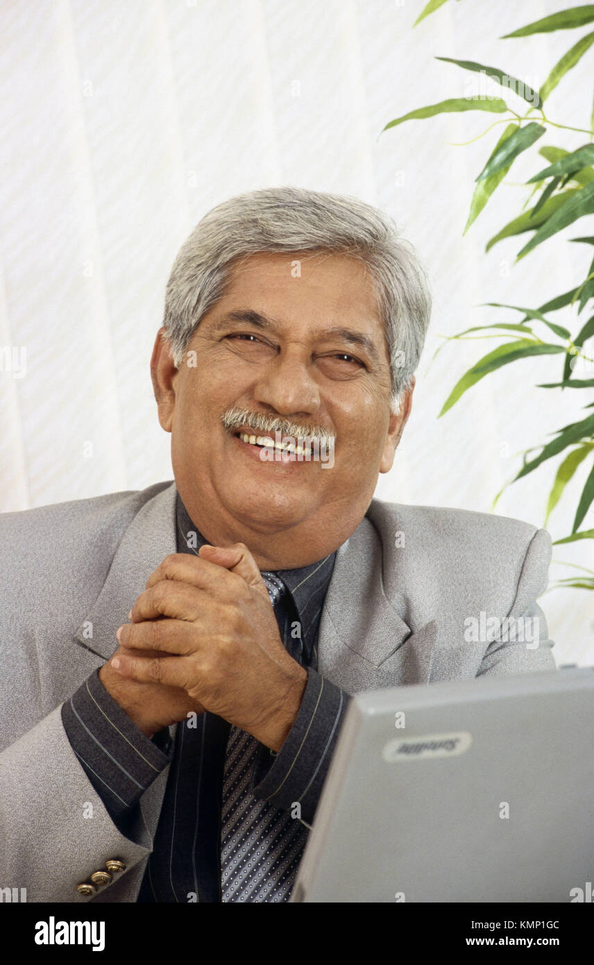 South Asian smiling Senior Citizen in front of his laptop Stock Photo ...