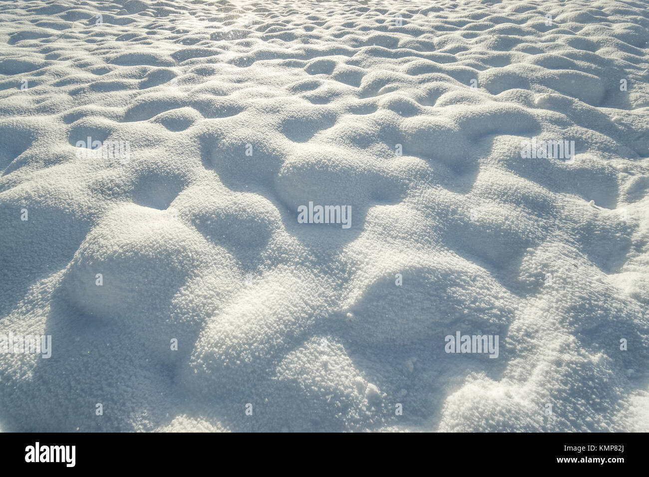 Fresh hilly snow surface background and drifting snowflakes. Bumpy snow ...