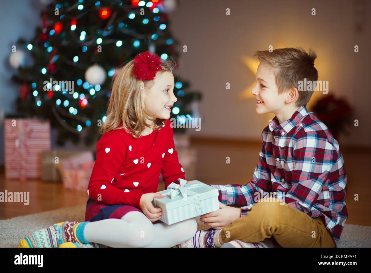 Two happy children in new year eve with presents near New Year Tree at ...