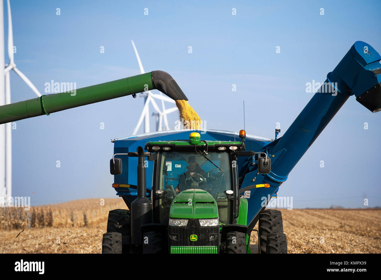 COMBINE LOADING CORN INTO HOPPER WITH VIEW OF WINDMILLS ON A FAMILY ...