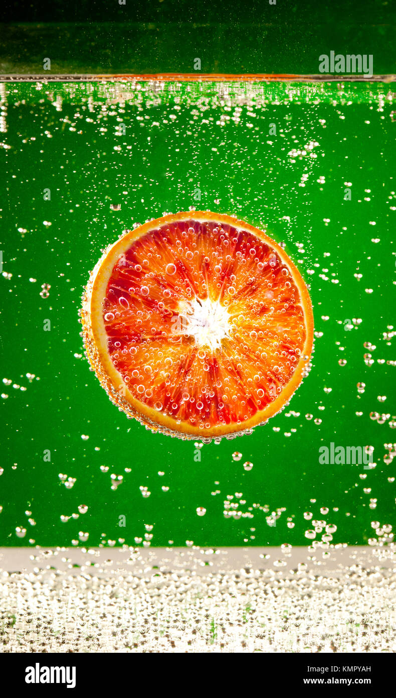 fresh red orange falls in water on a green background Stock Photo - Alamy