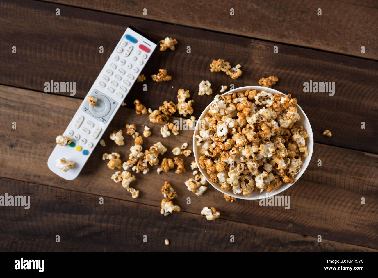 Caramel popcorn with tv remote on wooden table background. popcorn in a ...