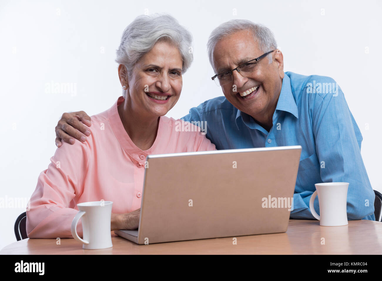 Happy senior couple using laptop sitting on table Stock Photo - Alamy