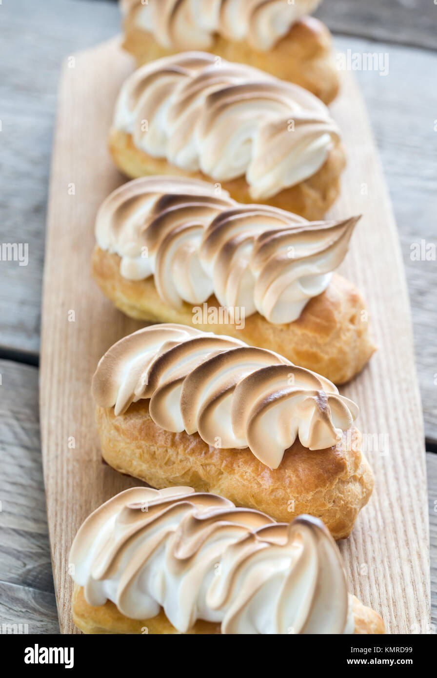 Eclairs with lemon curd and meringue on the wooden board Stock Photo ...