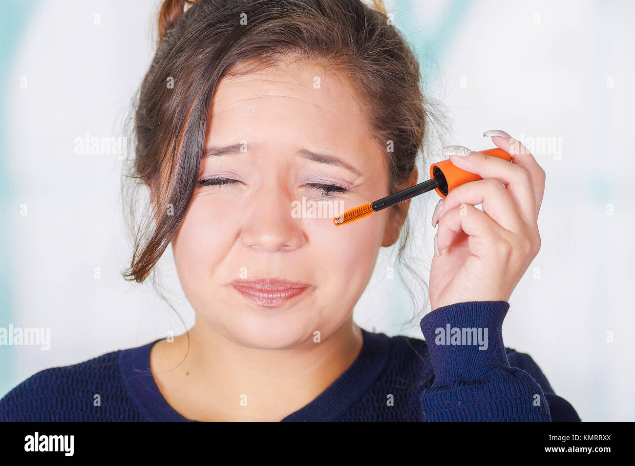 Close up of worried young woman, closing her eye while she is doing a ...