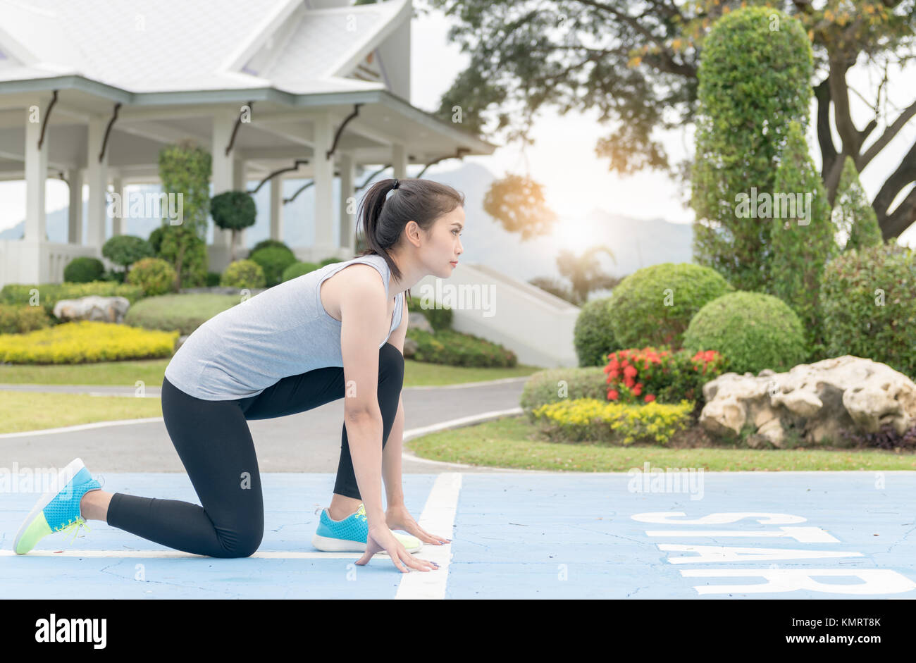 Fitness woman runner in start position at health park on morning ...