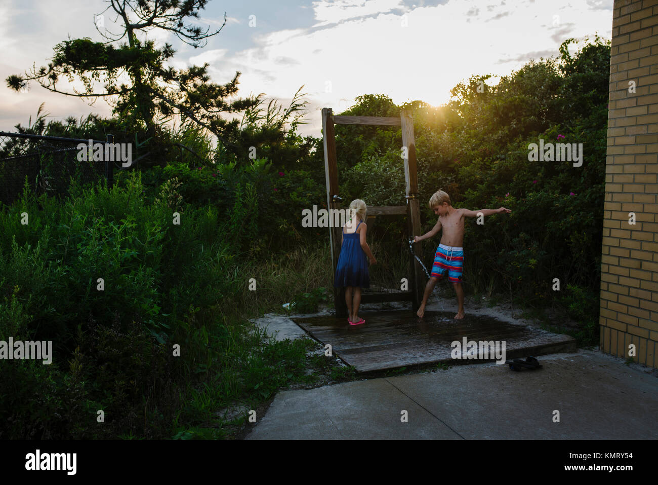 Siblings washing legs from tap water at Tobay Beach Stock Photo - Alamy