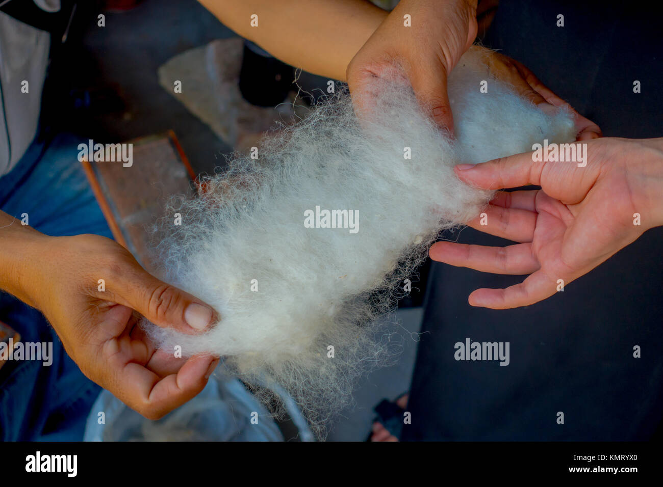Close up of a man holding in his hand a piece of wool to work on loom ...