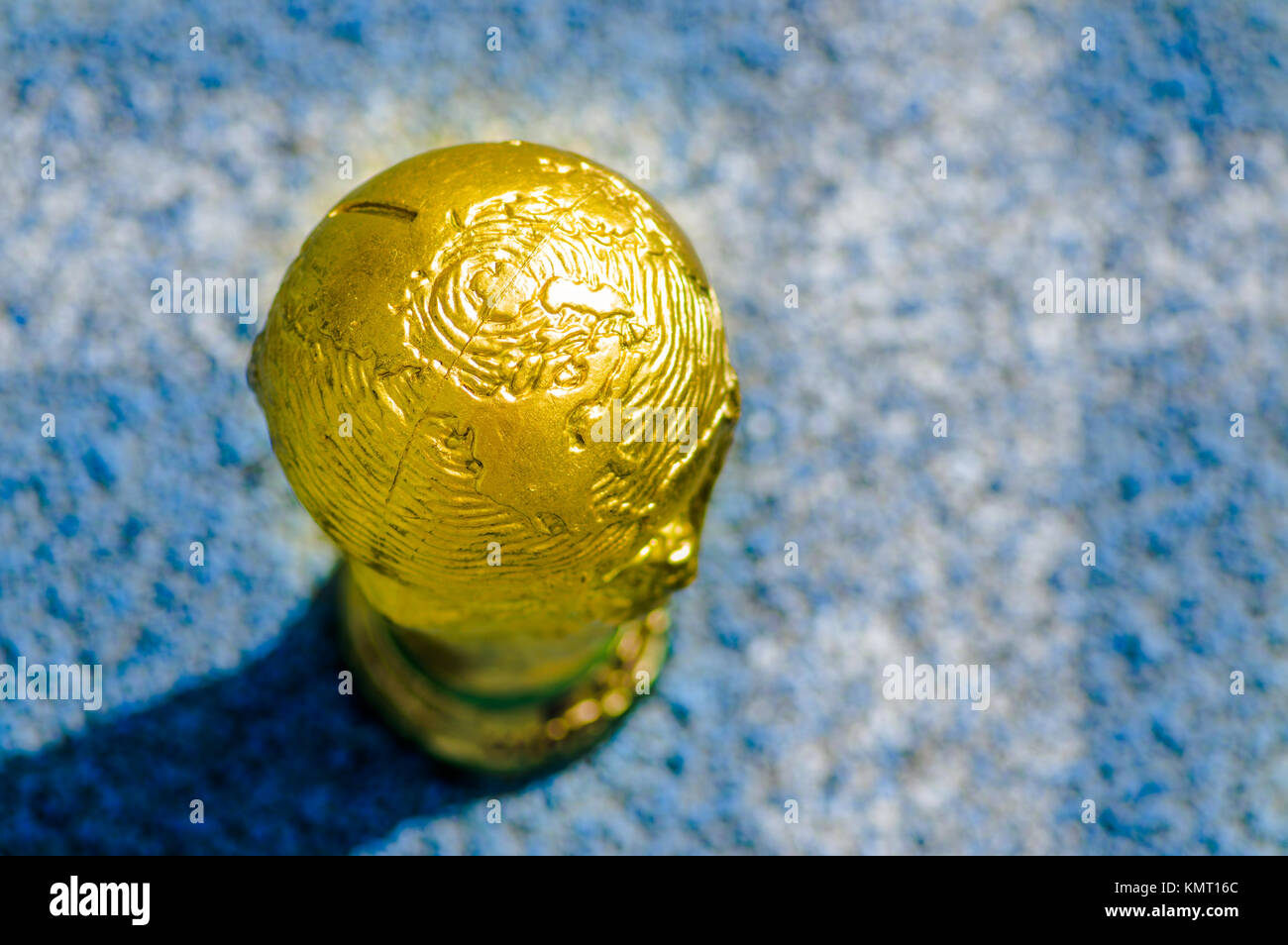Above view of fake golden trophy in the form of the globe over a blue ...