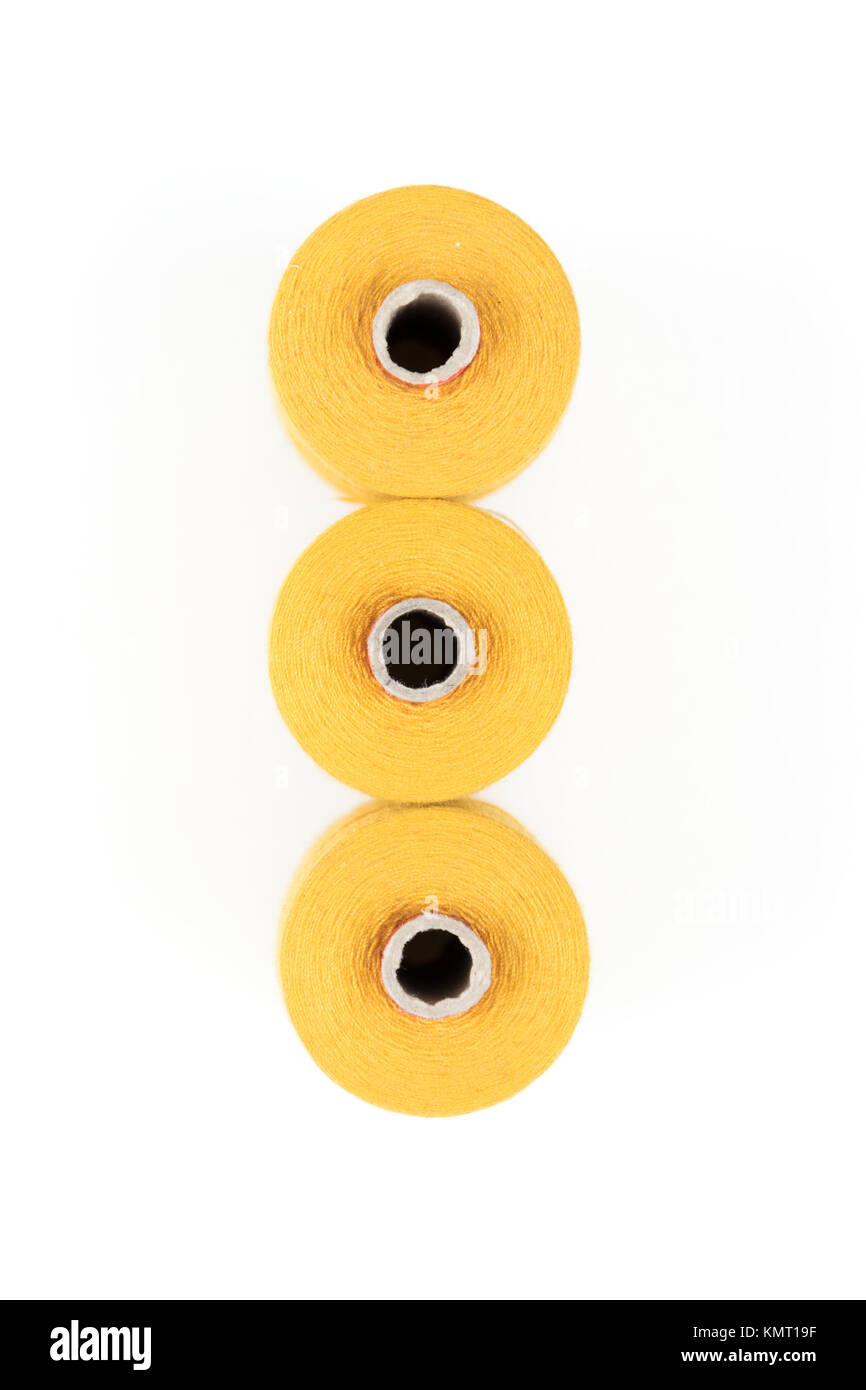 Yellow thread coils on white background, sewing and tailoring supplies ...
