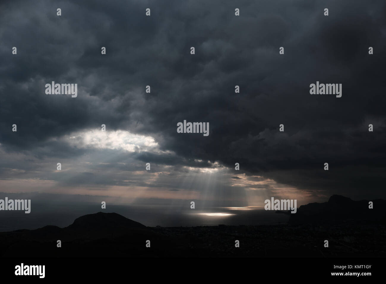 Sun rays through black rain clouds over hi-res stock photography and ...