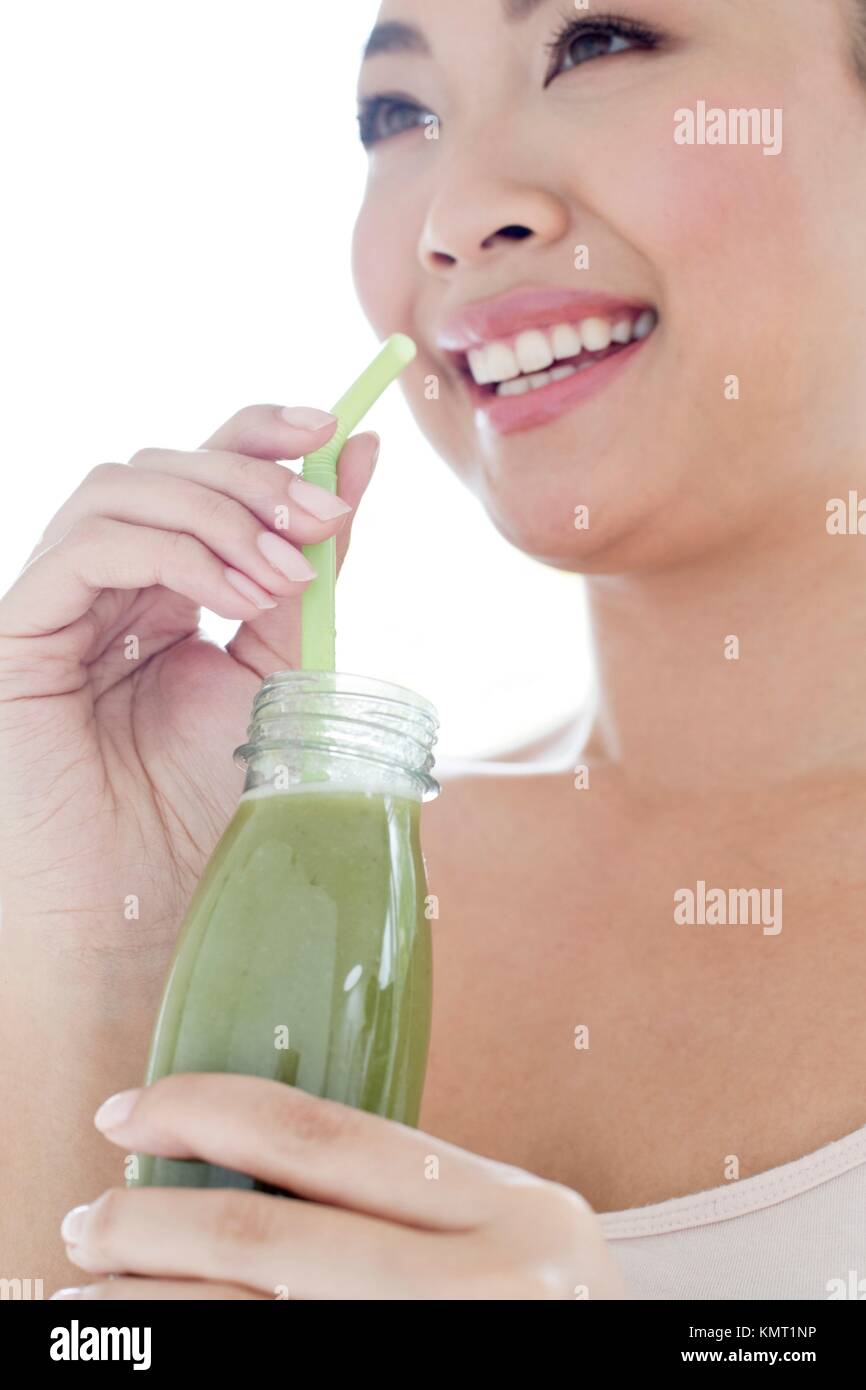 Young woman drinking green smoothie Stock Photo - Alamy