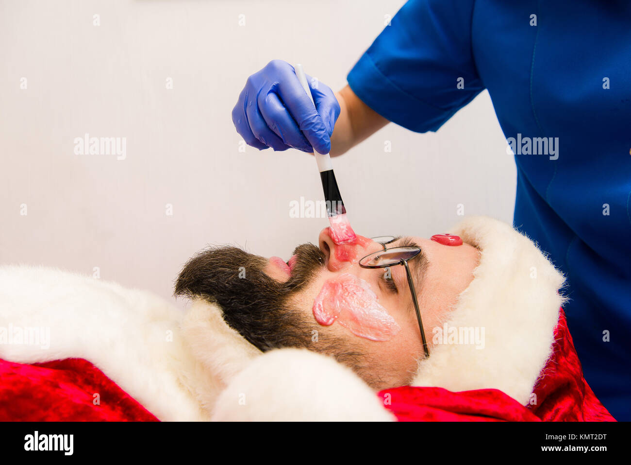 Santa Claus in beauty spa. Beautician applies facial mask. Spa facial ...