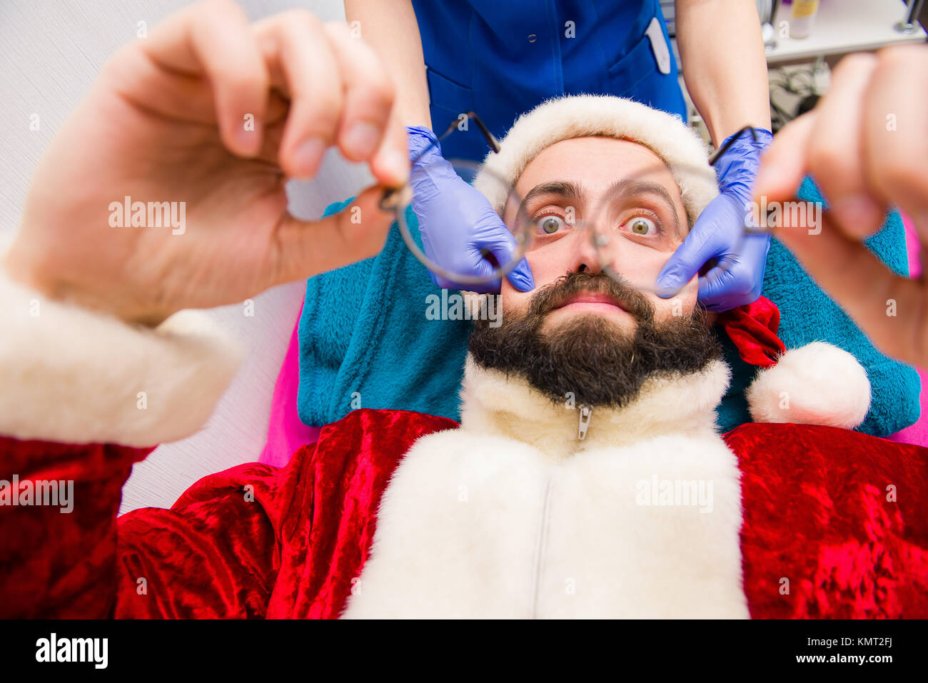 Christmas man in Santa Claus clothes in beauty spa. Facial massage ...
