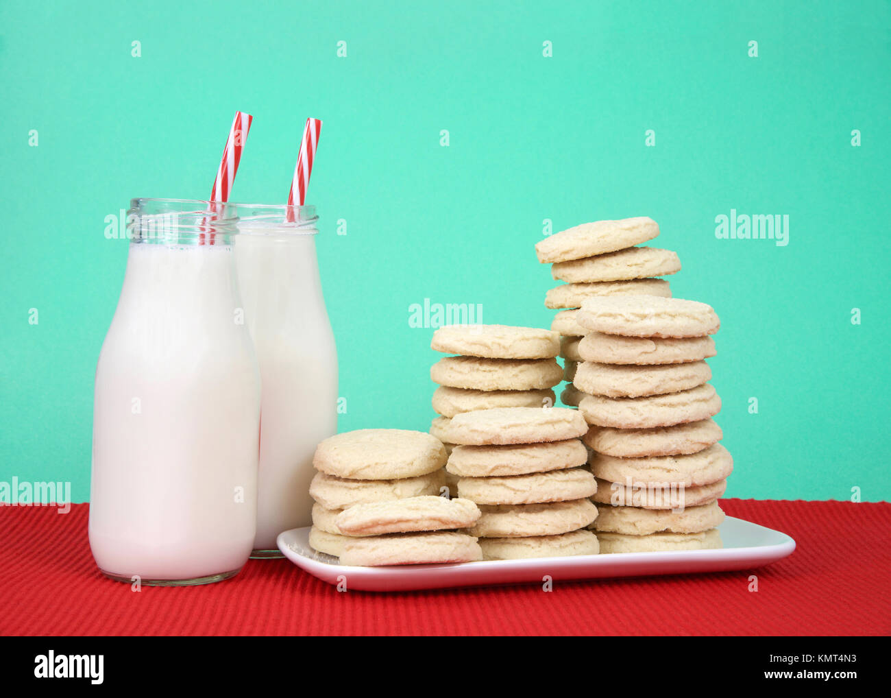 Sugar cookies stacked at multiple heights on a white rectangular plate ...