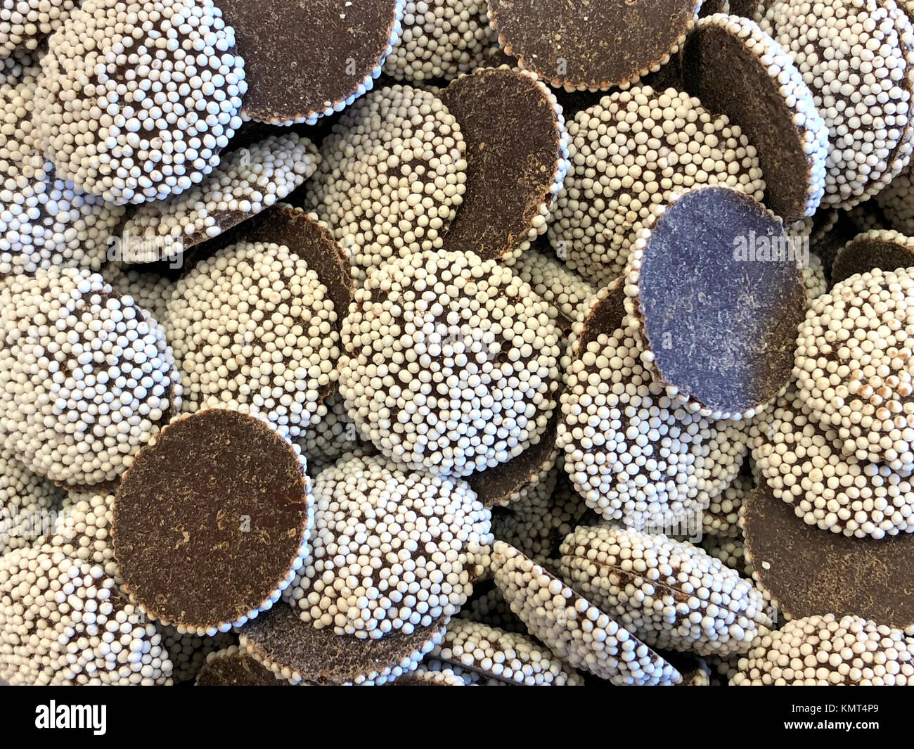 Chocolate candy discs covered with white candy cake sprinkles. Close up ...