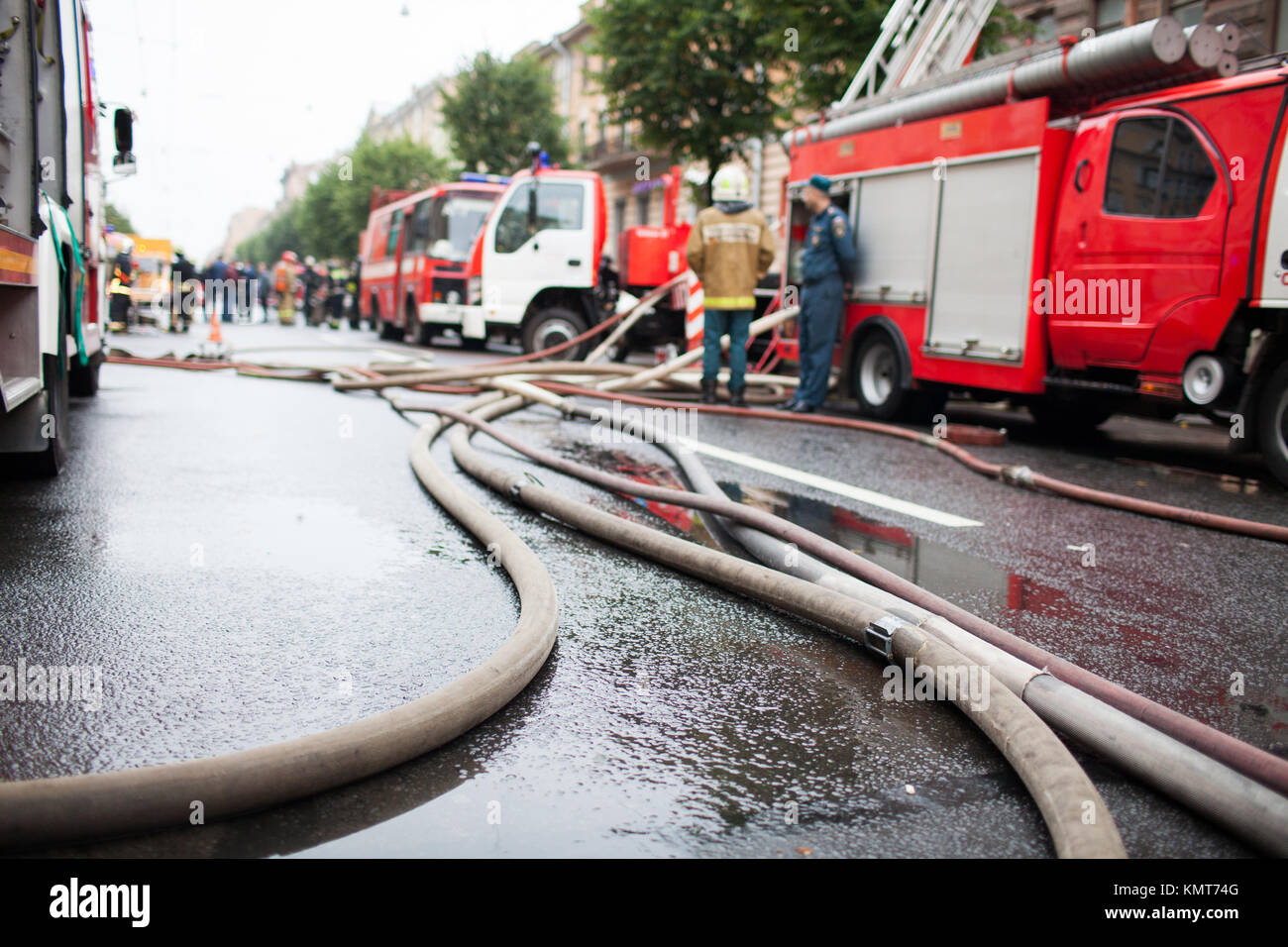 Fire hoses on the background of fire trucks and firefighters at work ...