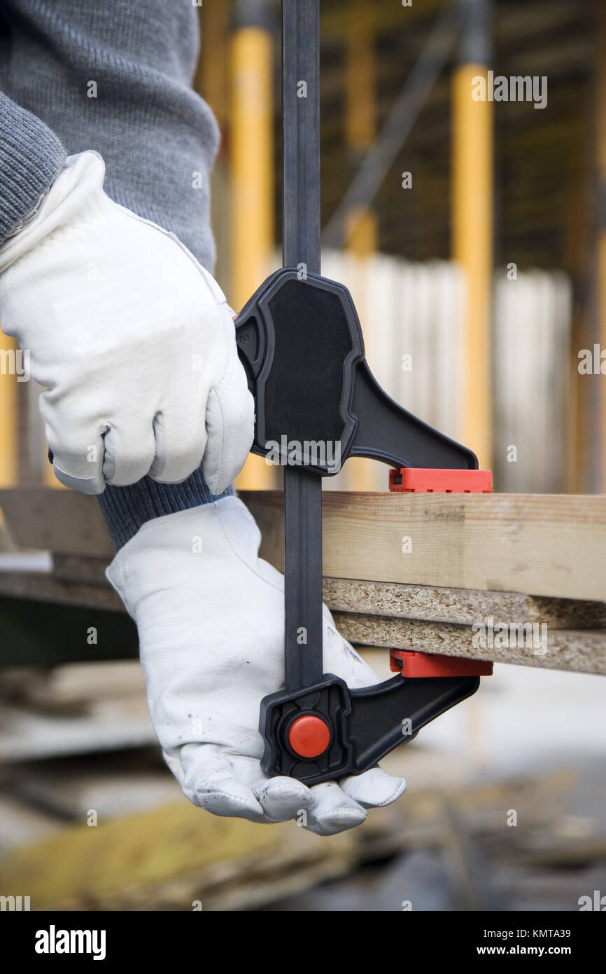 Construction worker holding timber with grip Stock Photo - Alamy