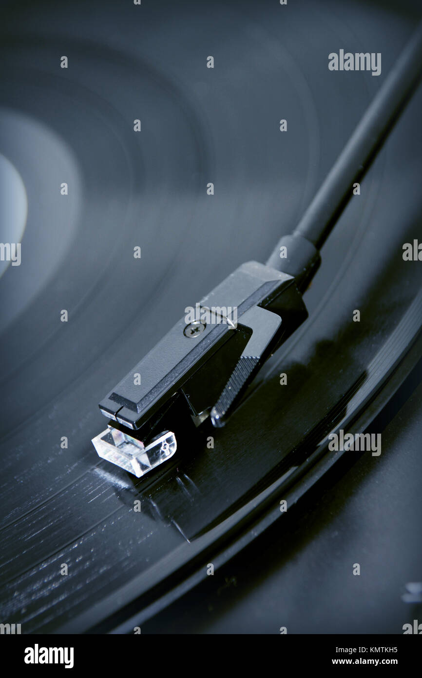 blue tinted close up of a stylus needle playing a vinyl record on a ...