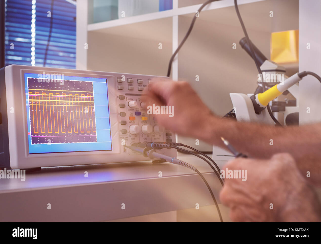 Senior male engineer or tech tunes oscilloscope in hardware service ...