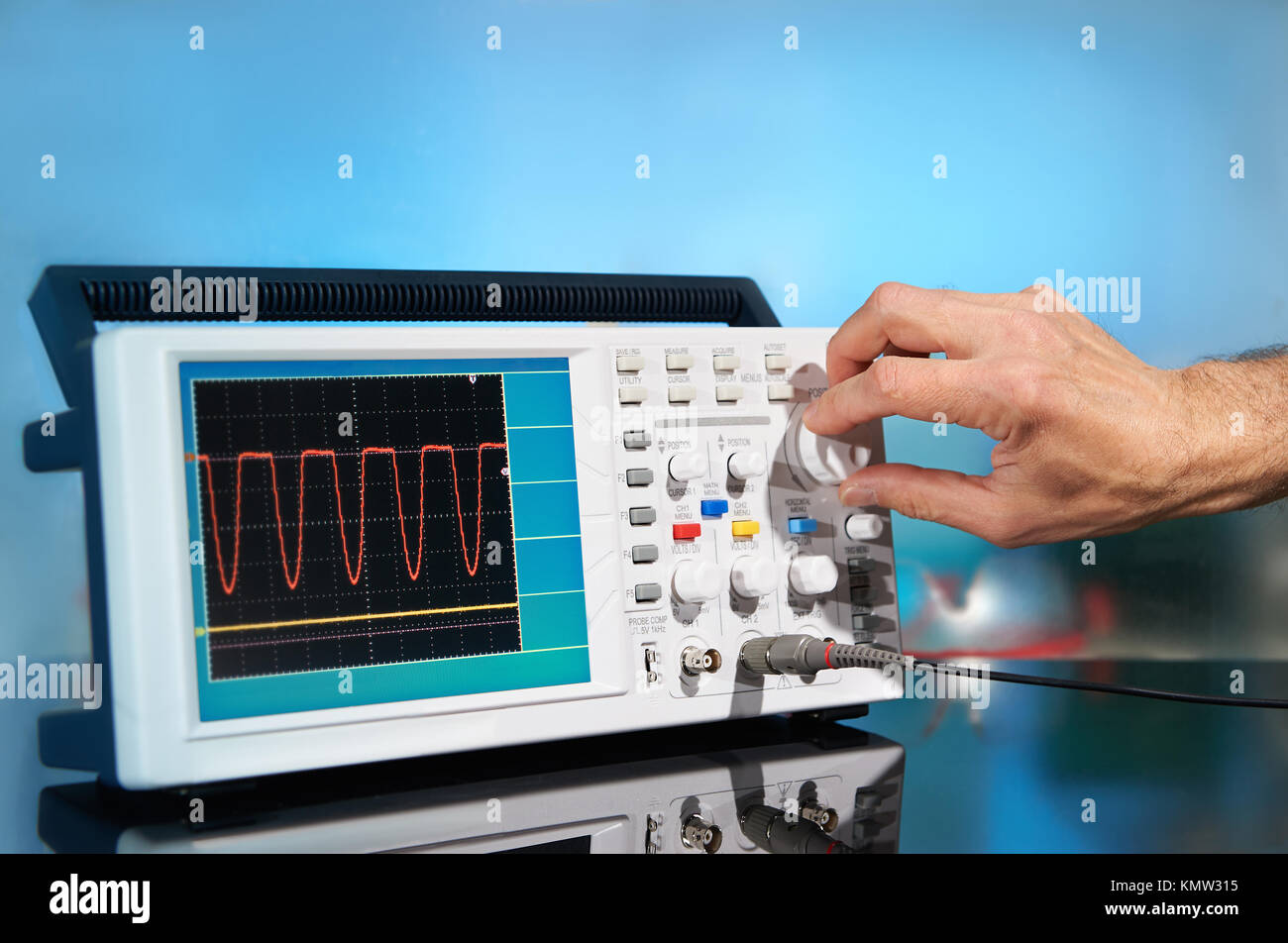 Modern electronic oscilloscope on abstract background, hand tuning a ...