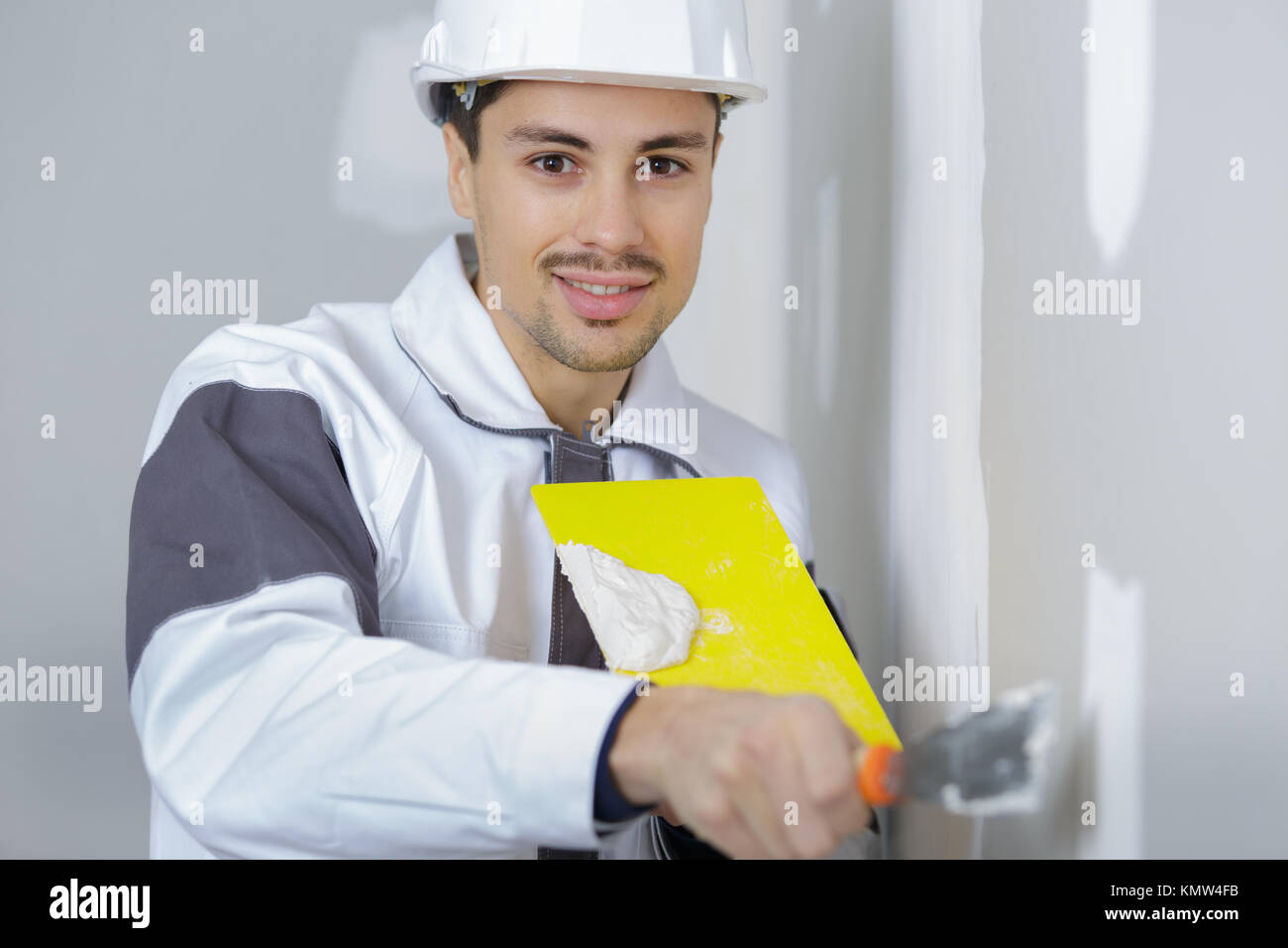 male plasterer in uniform polishing the wall Stock Photo - Alamy