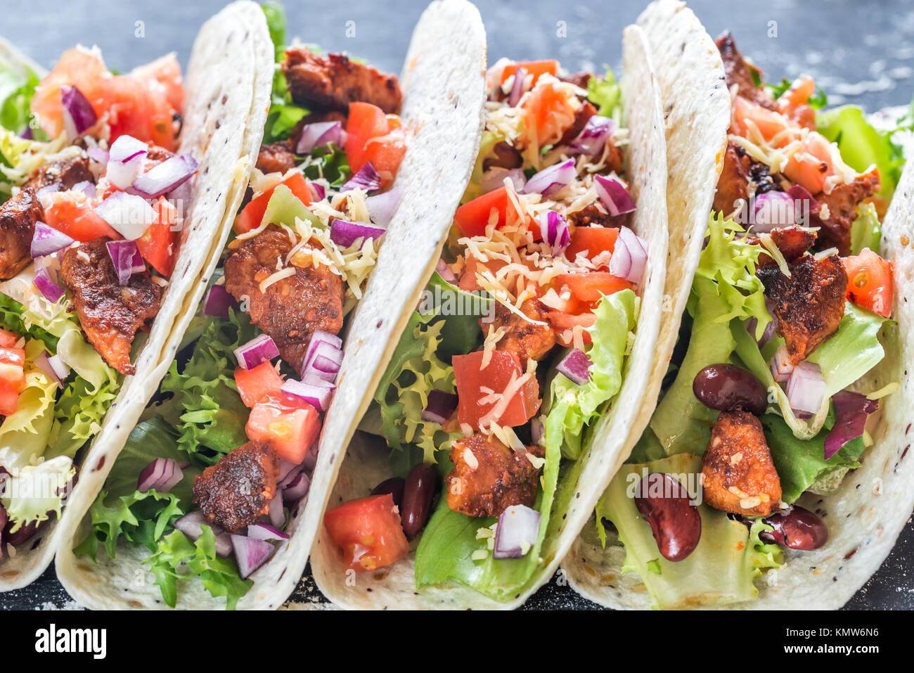 Four mexican tacos on a black background Stock Photo - Alamy